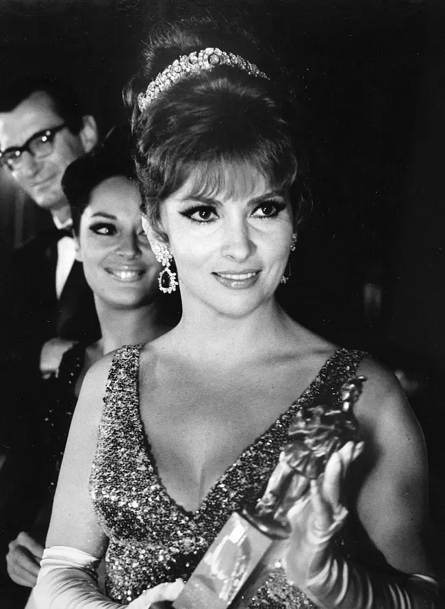 Gina Lollobrigida ווערינג פּלאַטינום, שמאַראַגד און דימענט ירינגז (1964) און אַ טראַנספאָרמינג בראַסלעט האַלדזבאַנד, וואָרן ווי אַ טיאַראַ, געמאכט פון פּלאַטינום מיט דיימאַנדז (1955) פאָטאָ # 1